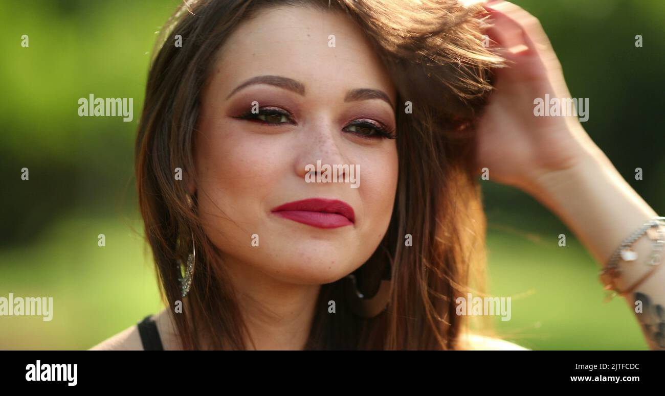 Pretty girl scratching face in outdoor park. Woman scratches lip ...