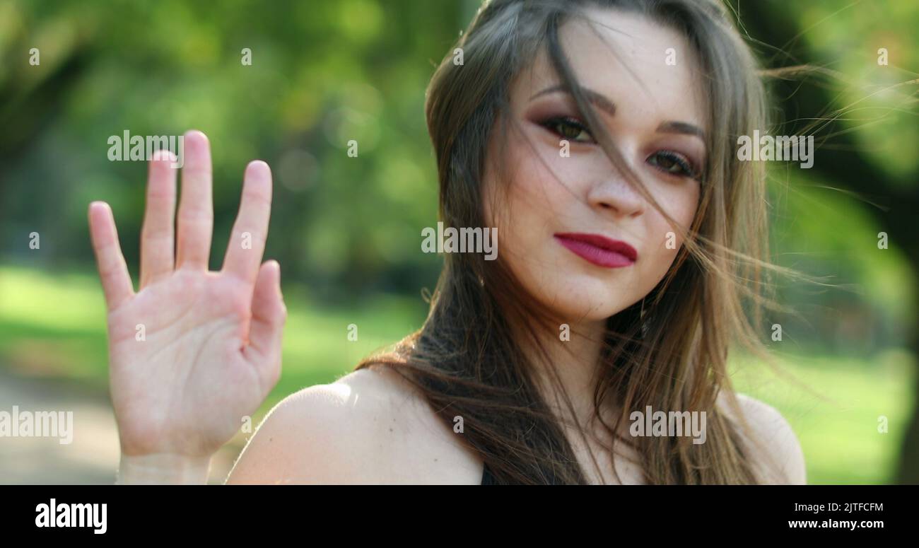 Pretty girl waving hello in outdoor park to camera Stock Photo - Alamy