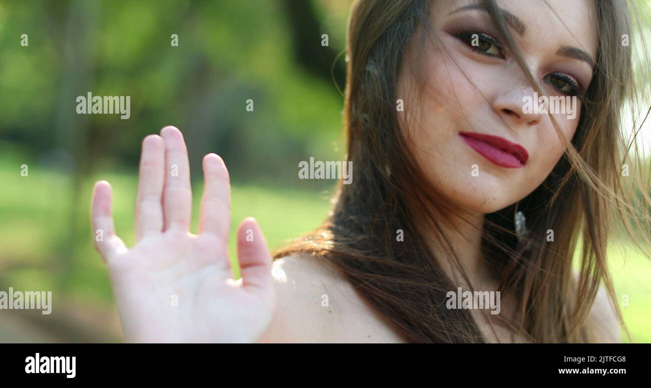 Pretty girl waving hello in outdoor park to camera Stock Photo - Alamy