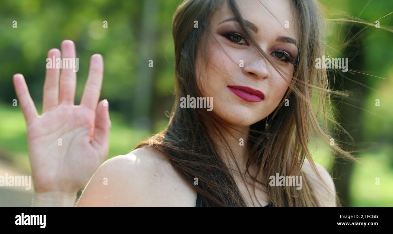 Pretty girl waving hello in outdoor park to camera Stock Photo - Alamy
