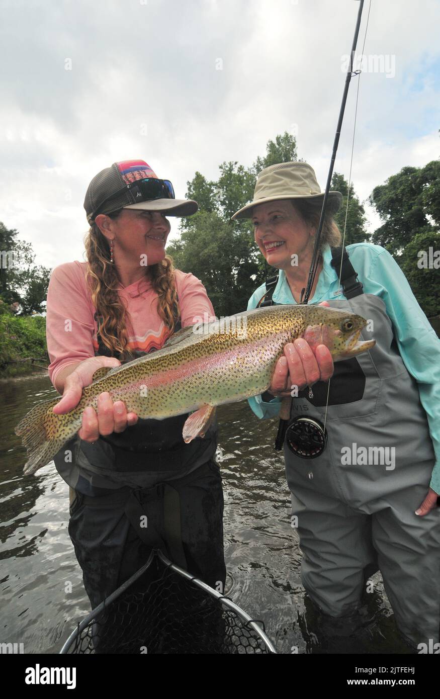 A guide holds up a beautiful rainbow trout caught in a quiet pool off a ...