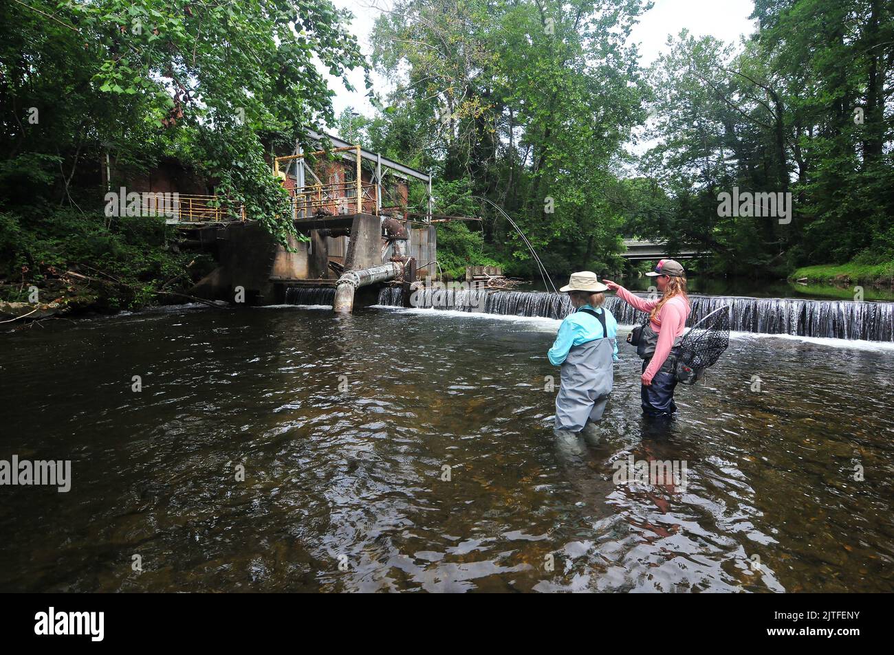 A trout angler with help from a guide works a quiet pool off a small ...