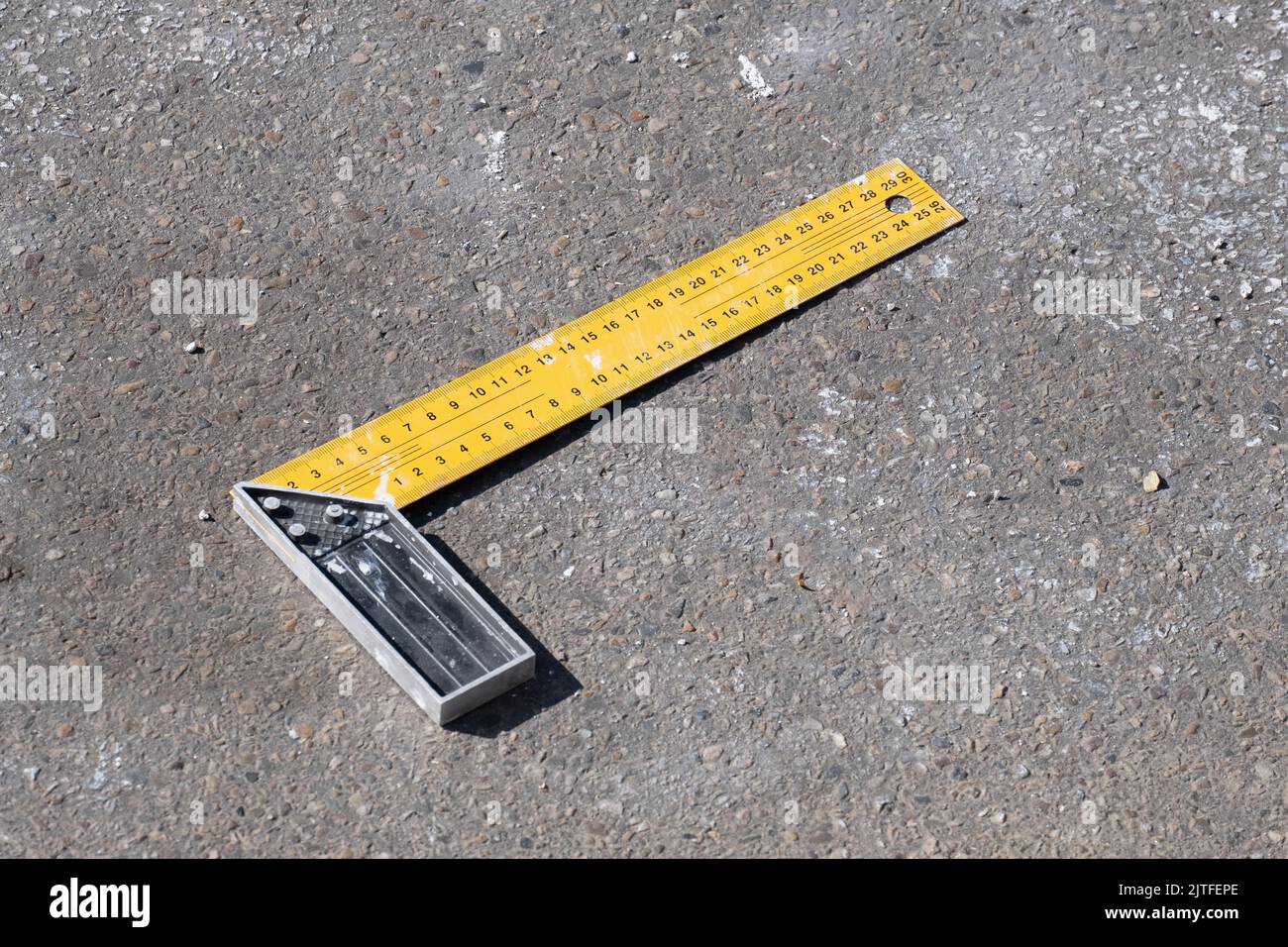 A mason's square marked with centimeters and inches on a construction ...