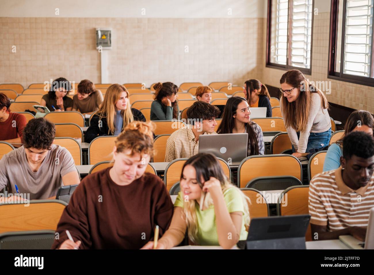 Teacher explaining to students individually while they do work. focus ...
