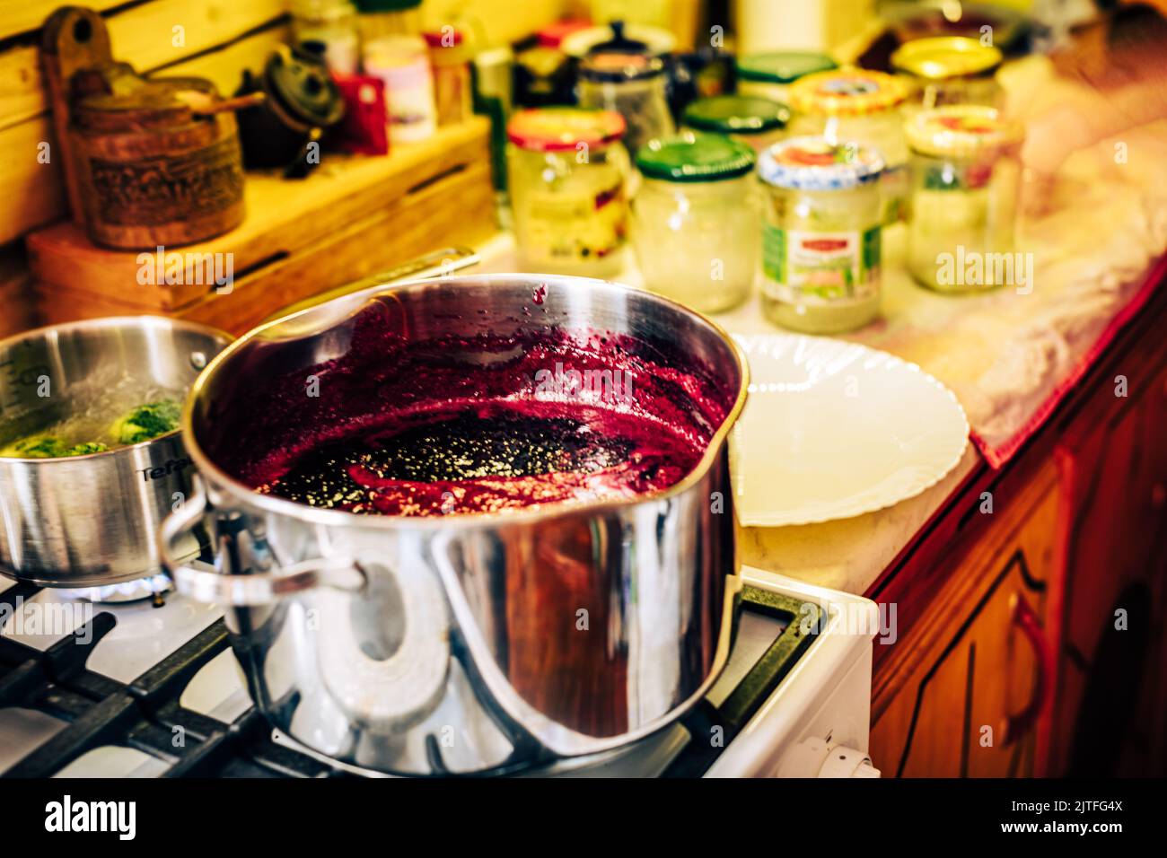 Sweet jam cooking closeup. Saucepan on stove. Kitchen background with ...