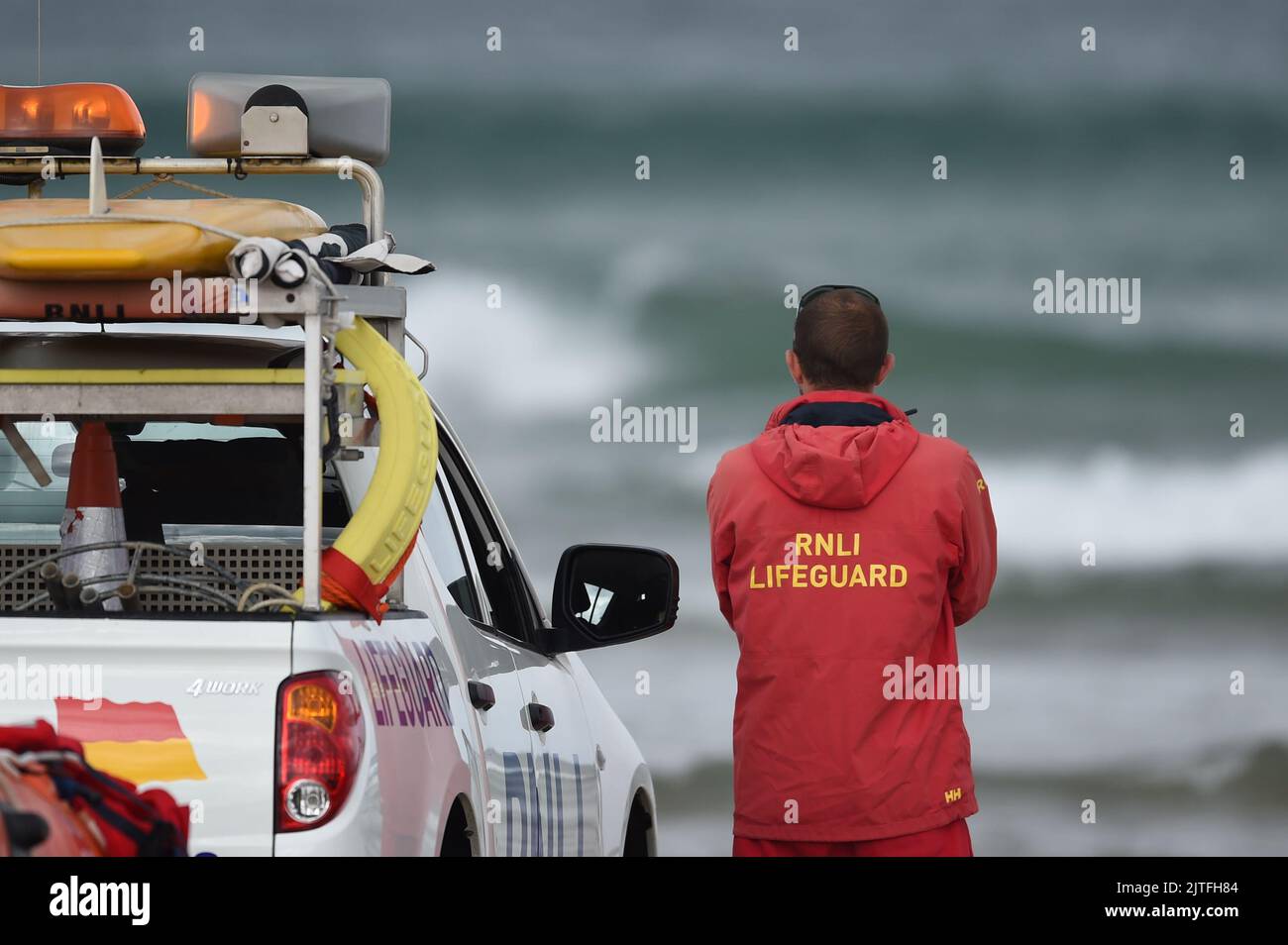 RNLI lifeguard on beach monitoring surfing competition Stock Photo - Alamy