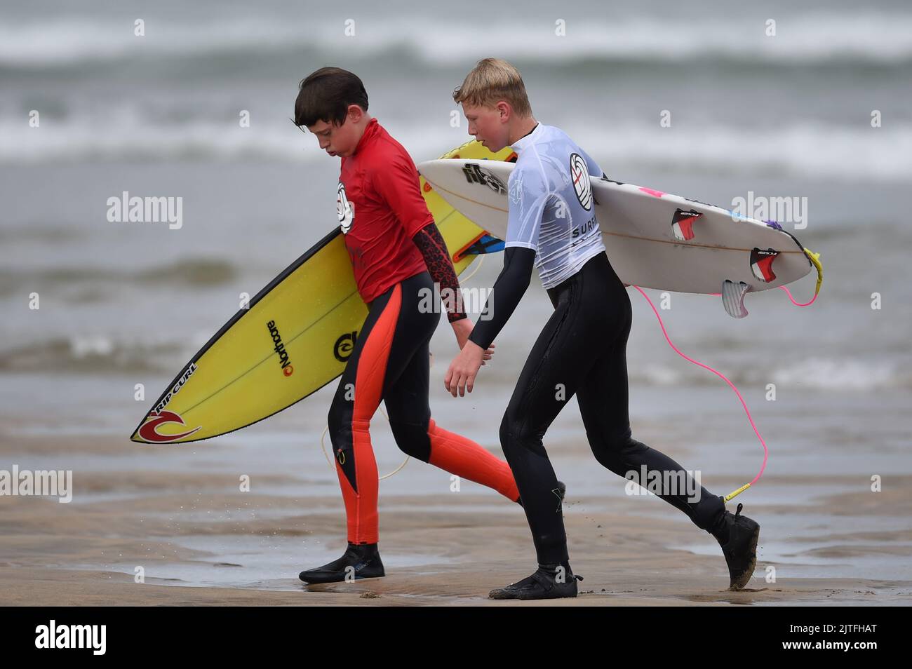 Two young male Surfers walking in the surf carrying surfboards Stock ...