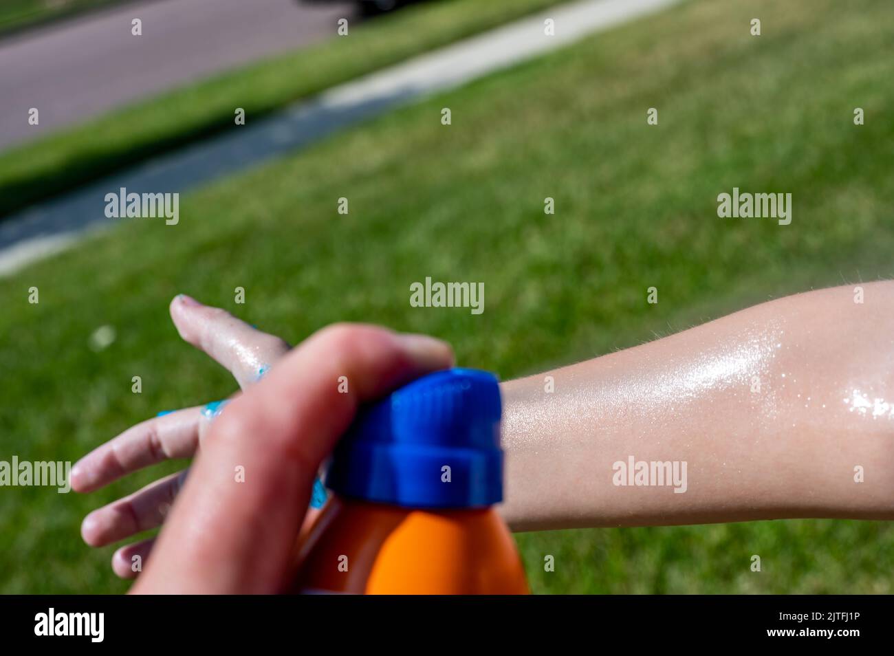Applying an aerosol spray sunscreen to a young child in the summer ...