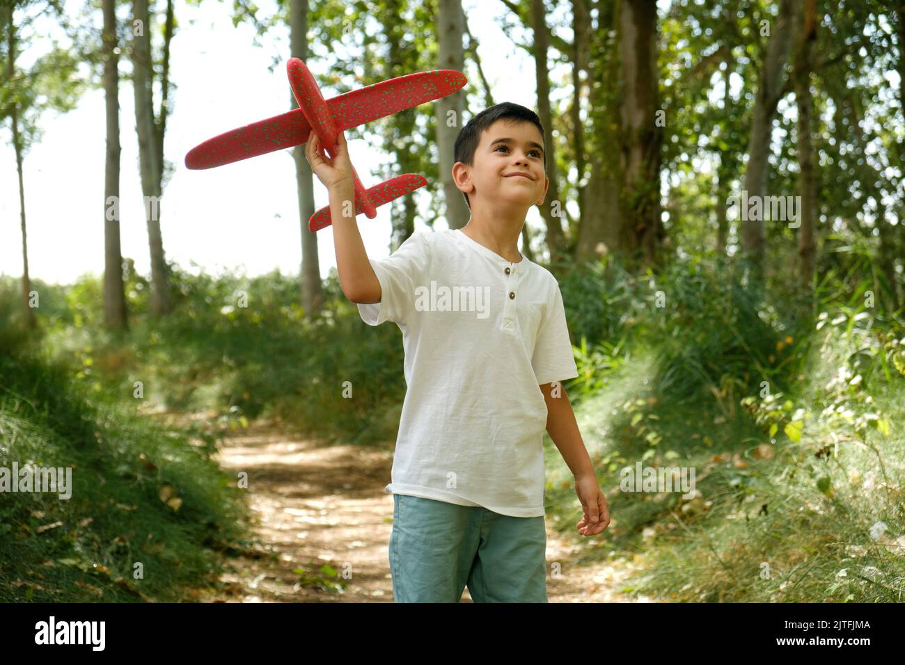child plays in nature with a toy airplane. Entertainment and fun in ...