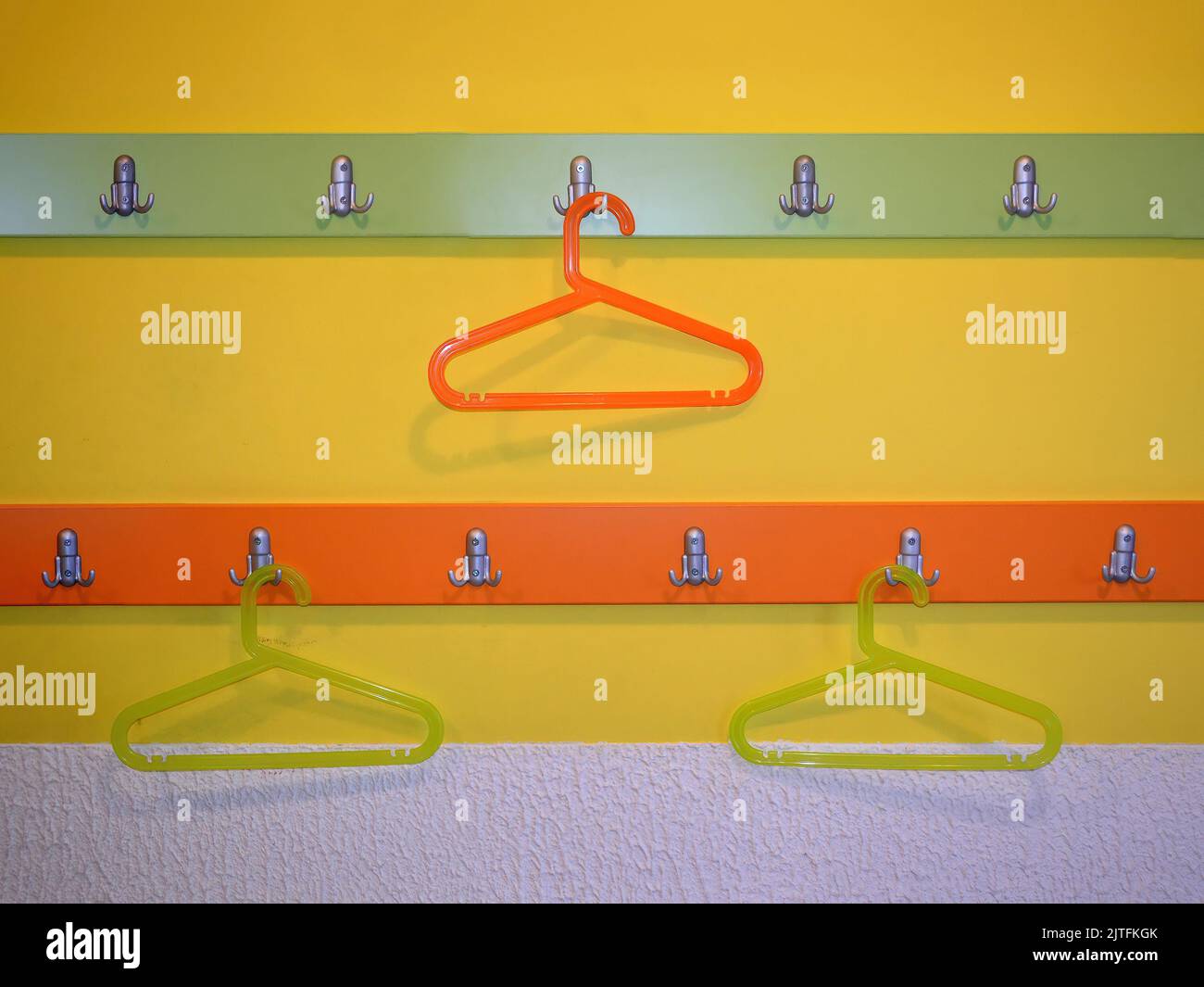 Three various colors hangers on the hooks on the wall Stock Photo - Alamy