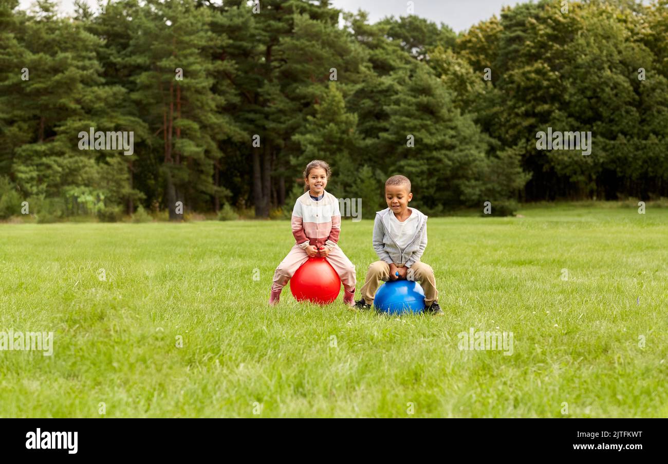 happy children bouncing on hopper balls at park Stock Photo - Alamy