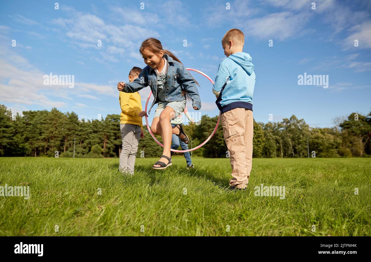 happy children playing game with hula hoop at park Stock Photo - Alamy
