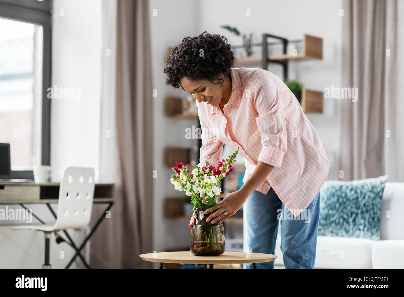 happy woman placing flowers on table at home Stock Photo - Alamy