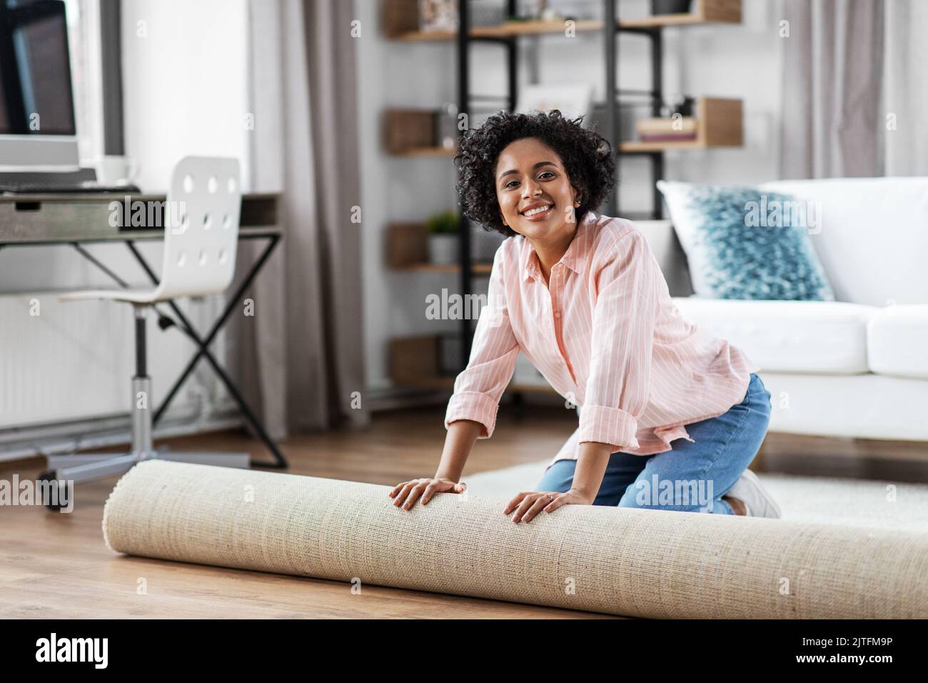 young woman unfolding carpet at home Stock Photo - Alamy