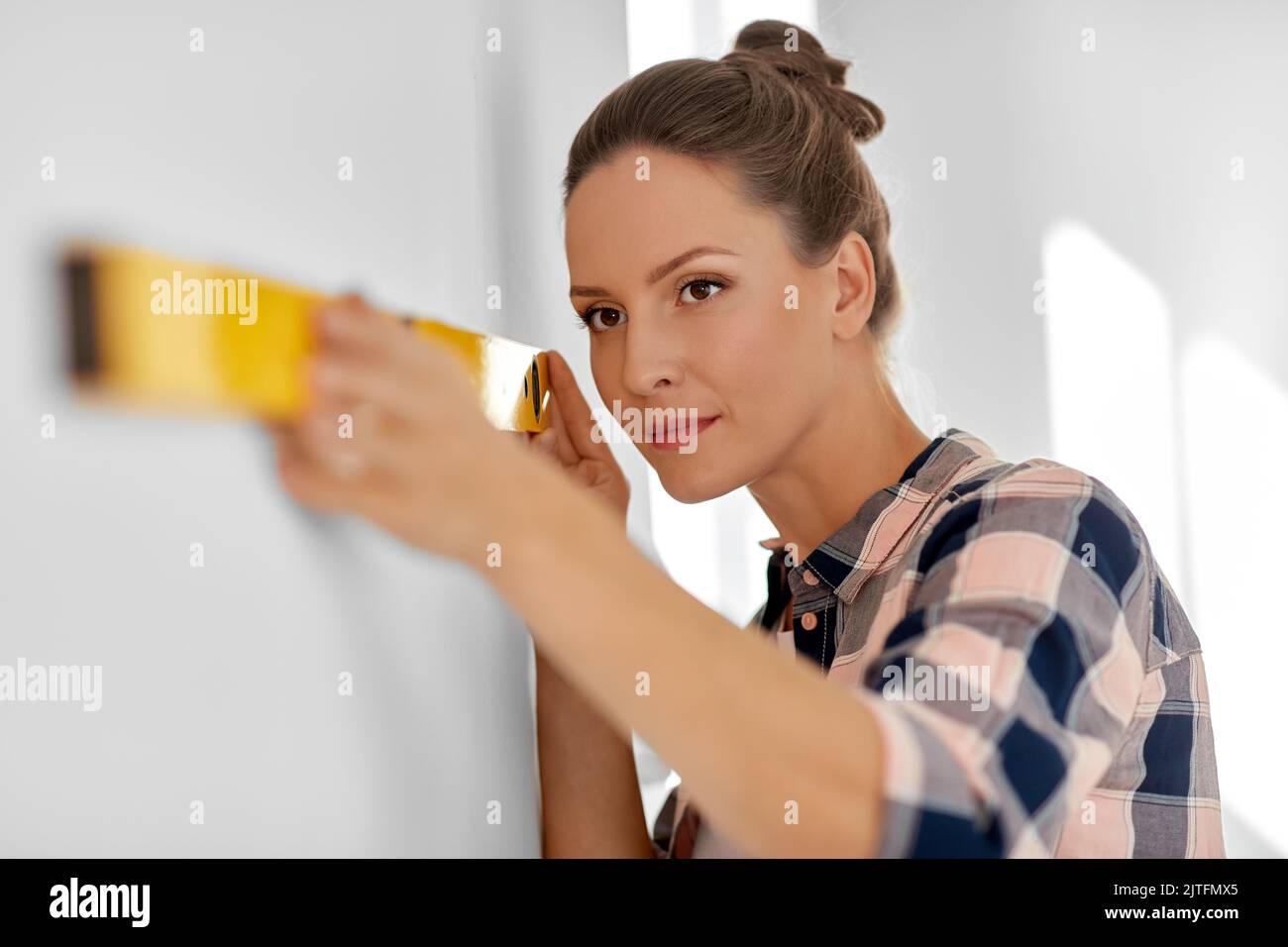 woman with level measuring wall at home Stock Photo - Alamy