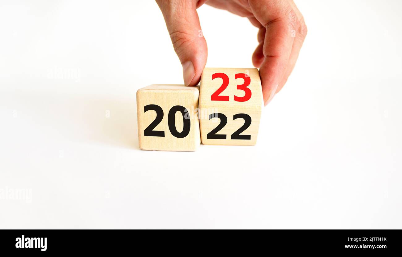 2023 happy new year symbol. Businessman turns a cube, symbolize the change from 2022 to the new ...