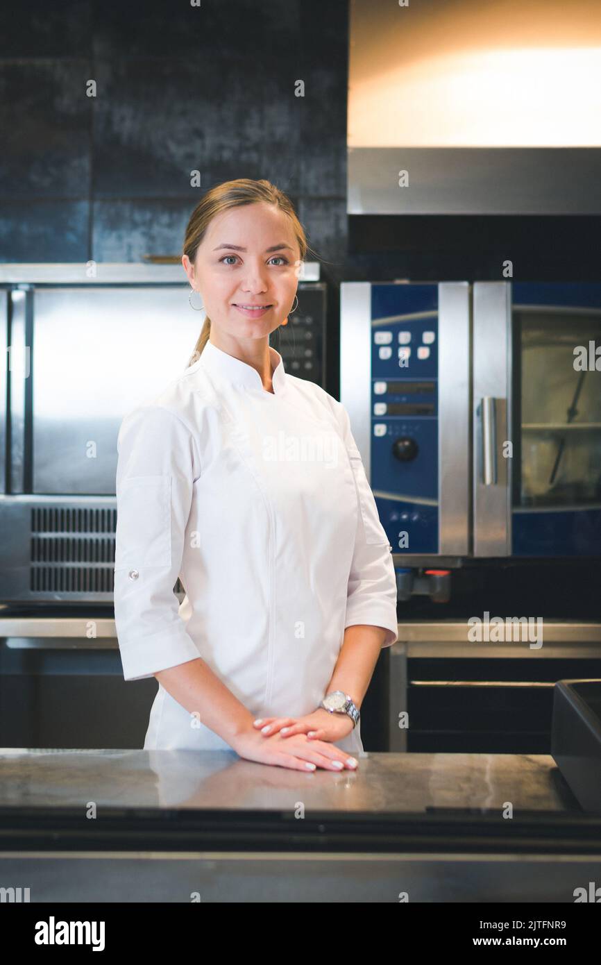 Portrait of confident and smiling young woman chef dressed in white ...
