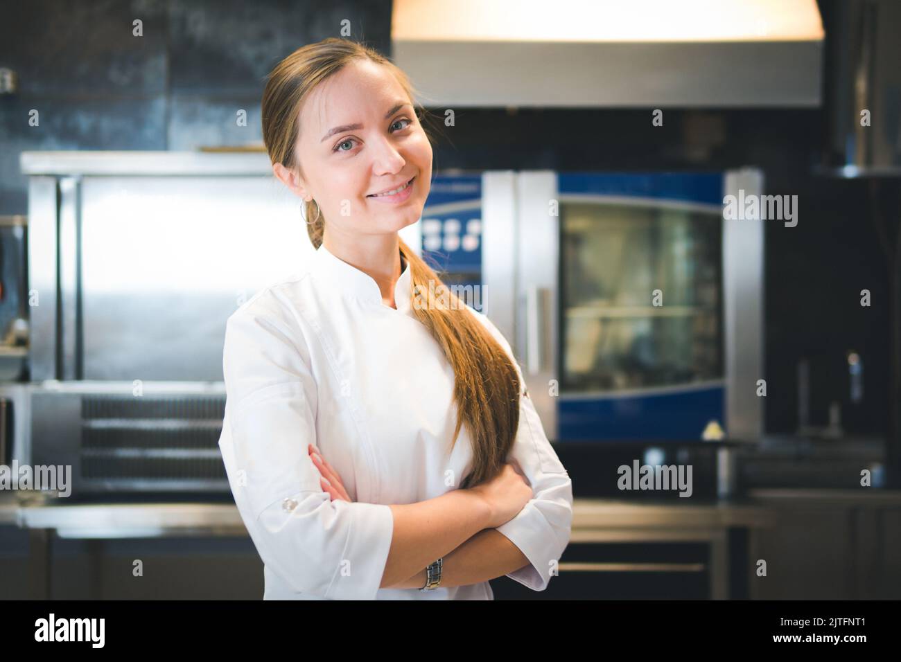 Portrait of confident and smiling young woman chef dressed in white ...