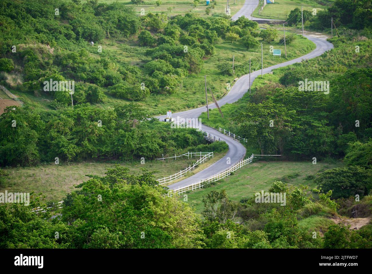 A shot of an empty sloped road with short white fences on each side ...