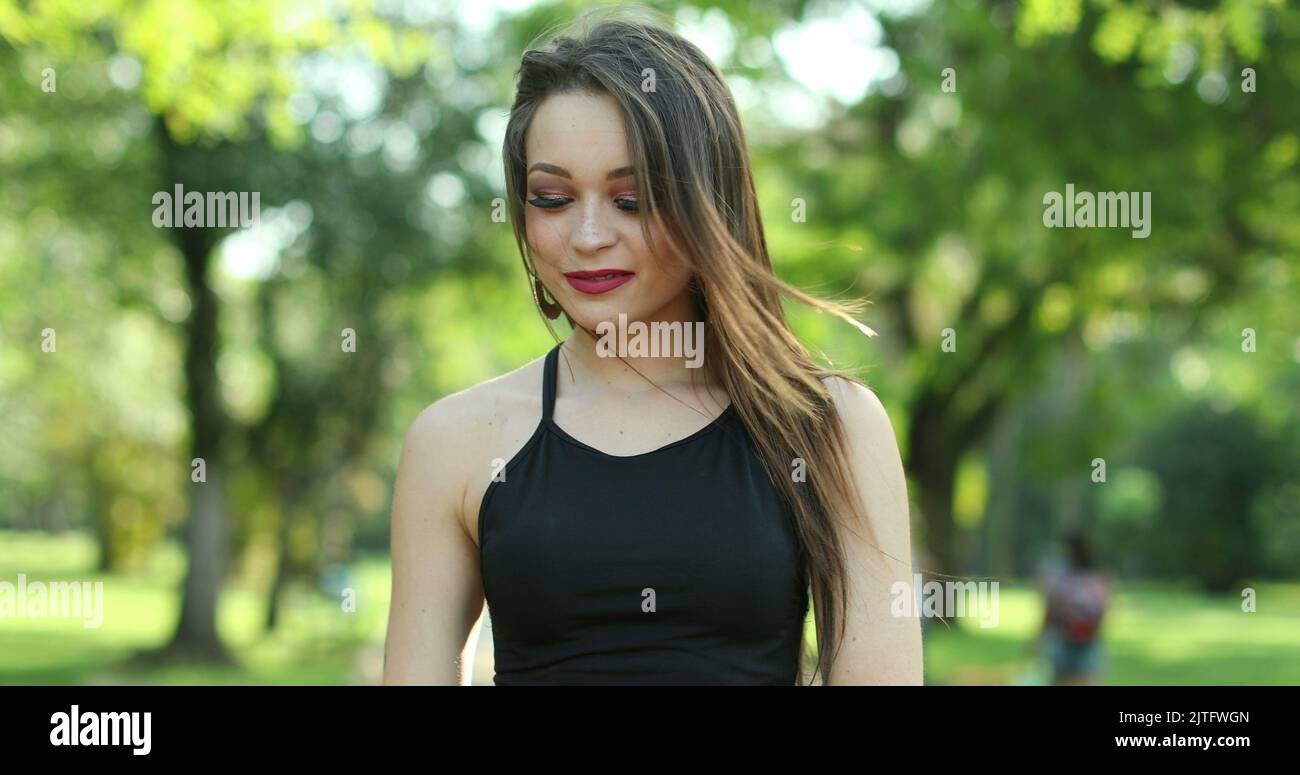 Pretty millennial girl standing looking to camera outside in nature ...