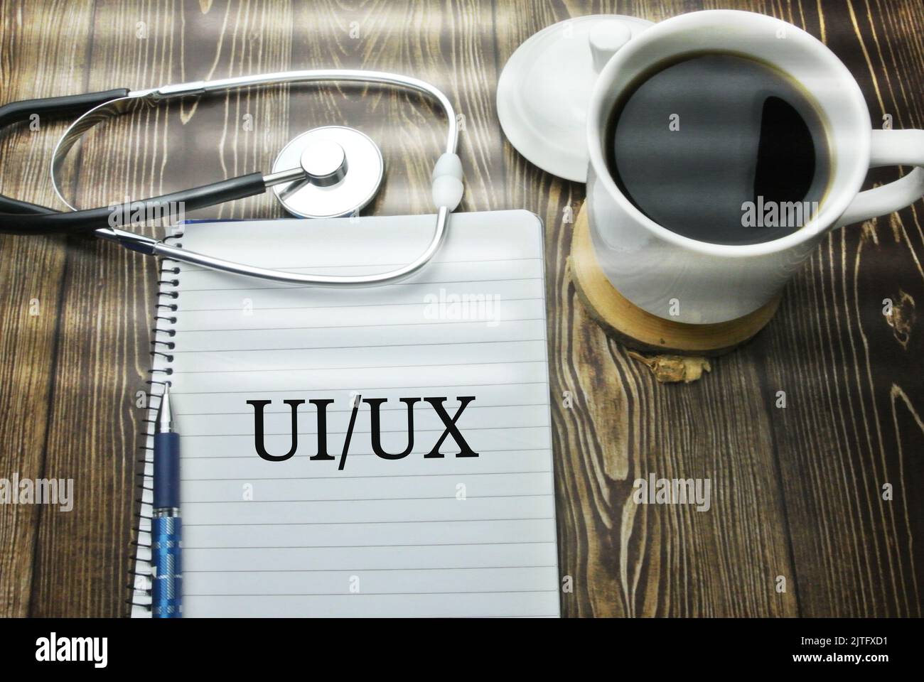 A cup of coffee, phonendoscope, pen and notebook with UI UX inscription ...