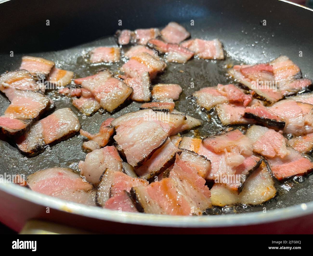 Roasted chopped crispy bacon strips slices in a Hot Skillet frying pan ...