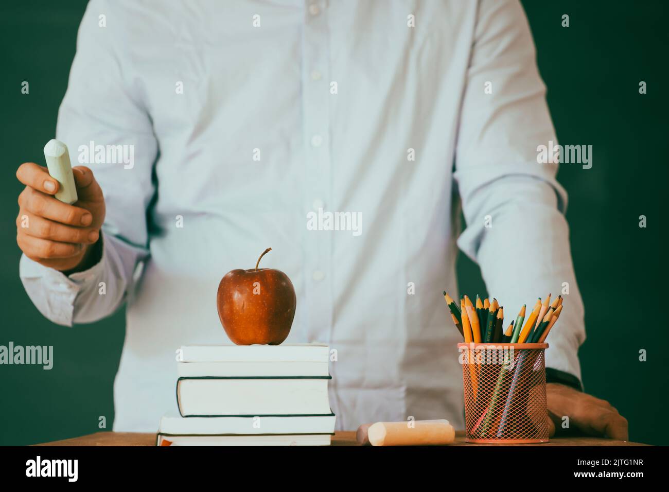 Back to school concept: teacher with books and chalk in the classroom ...