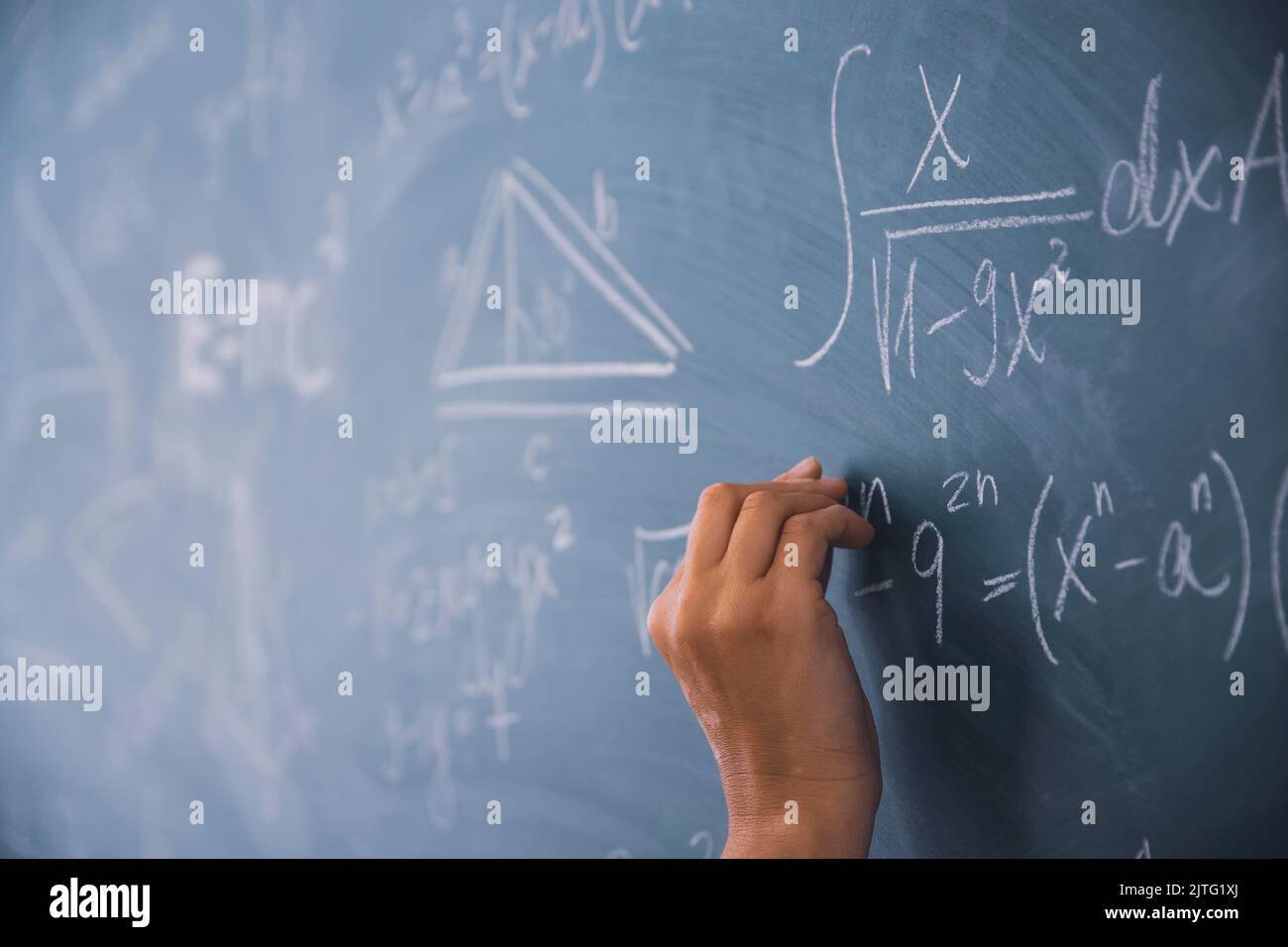 Close-up shot of a hand holding chalk and writing mathematical ...