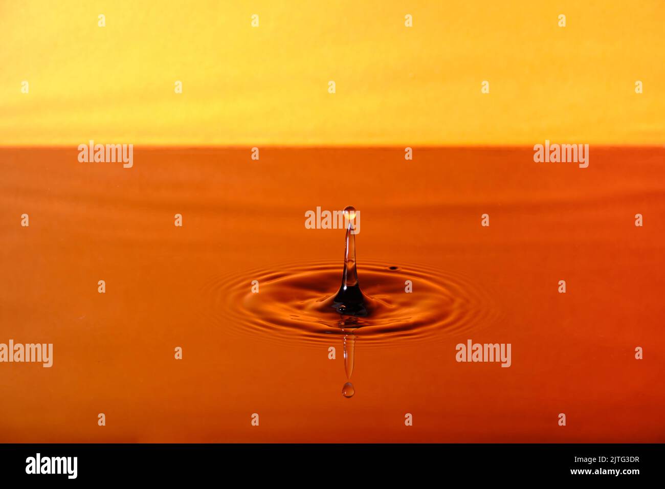 Splash drop of water with diverging water circles, on orange background ...