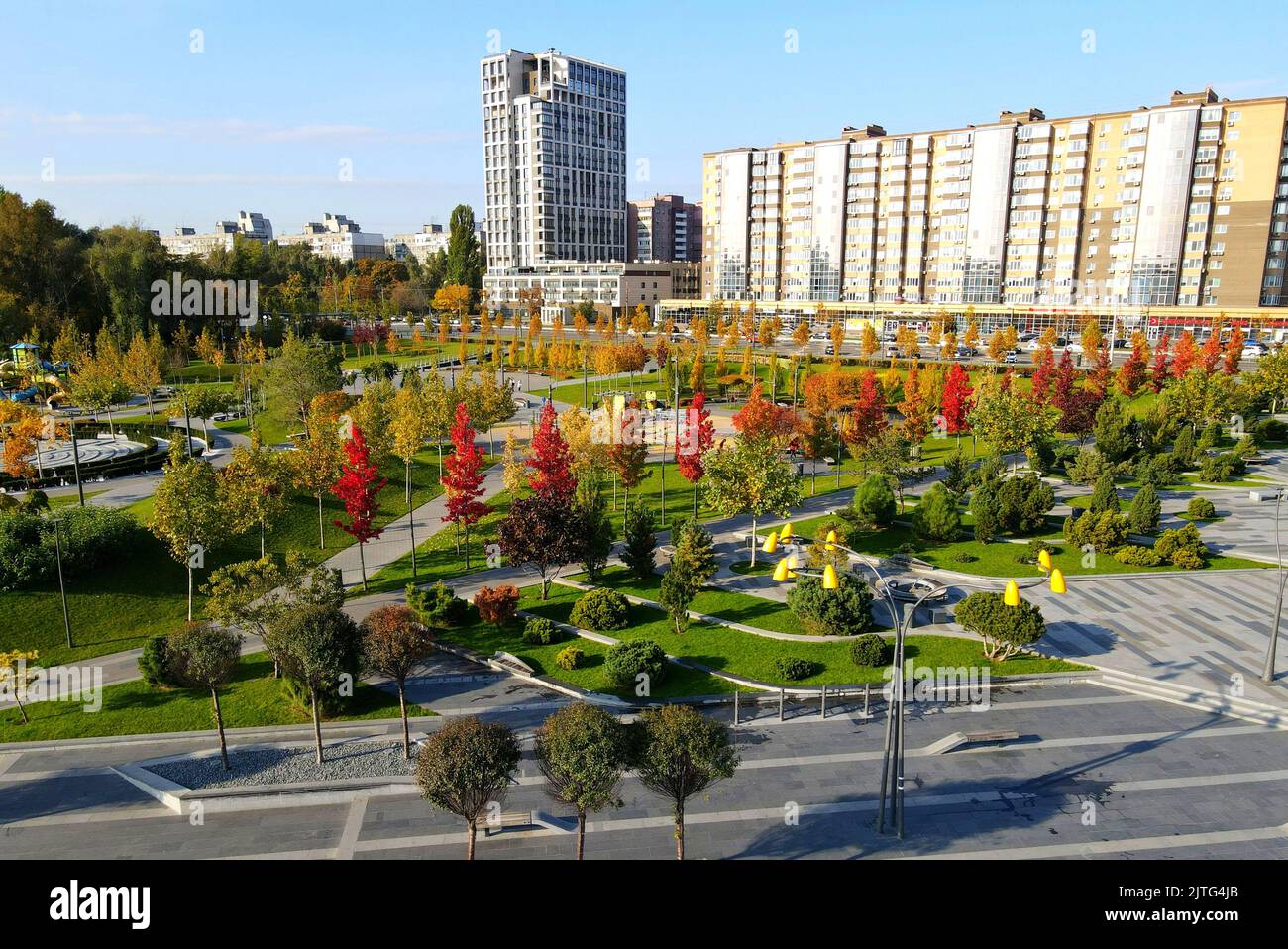 Autumn park, red trees against tall houses, buildings, landscape ...