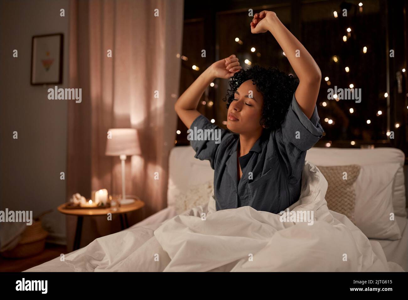 sleepy woman stretching in bed at night Stock Photo - Alamy