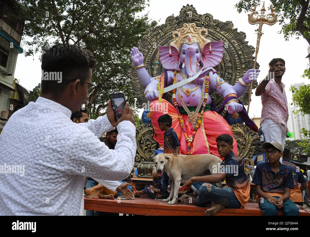 A dog and devotees pose next to the idol of elephant headed Hindu god ...