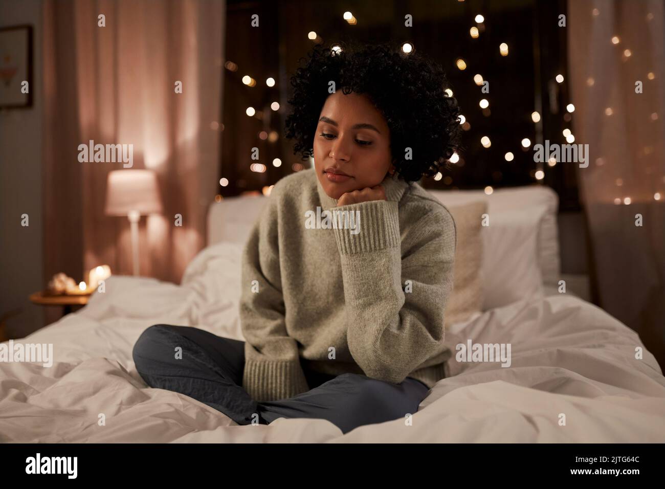 sad woman in sweater on bed at home at night Stock Photo - Alamy