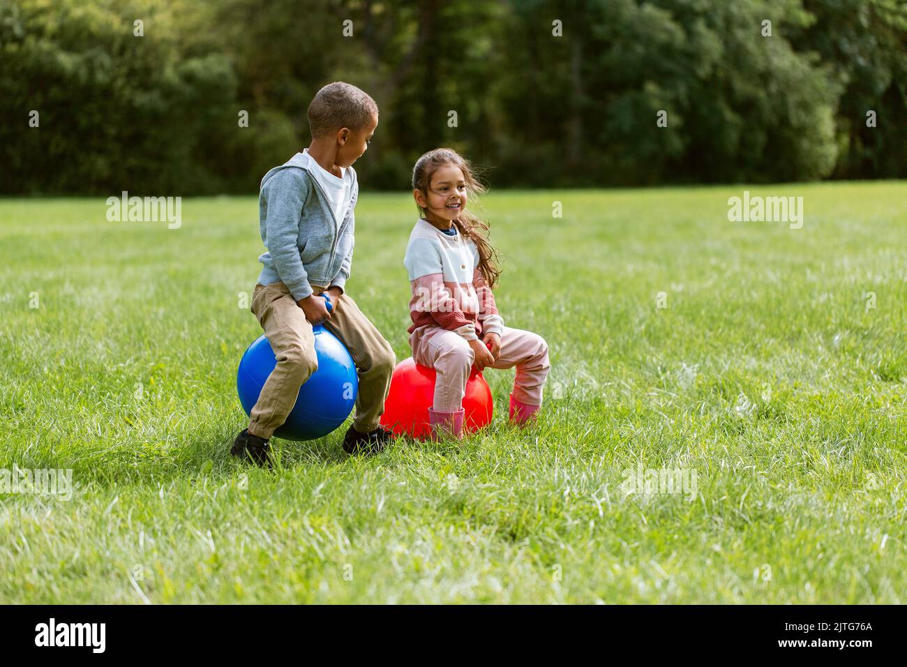 happy children bouncing on hopper balls at park Stock Photo - Alamy