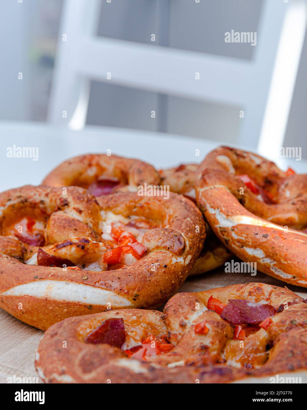 Traditional Bavarian pretzels stuffed with cheese, dry sausage and paprika on a white table ...