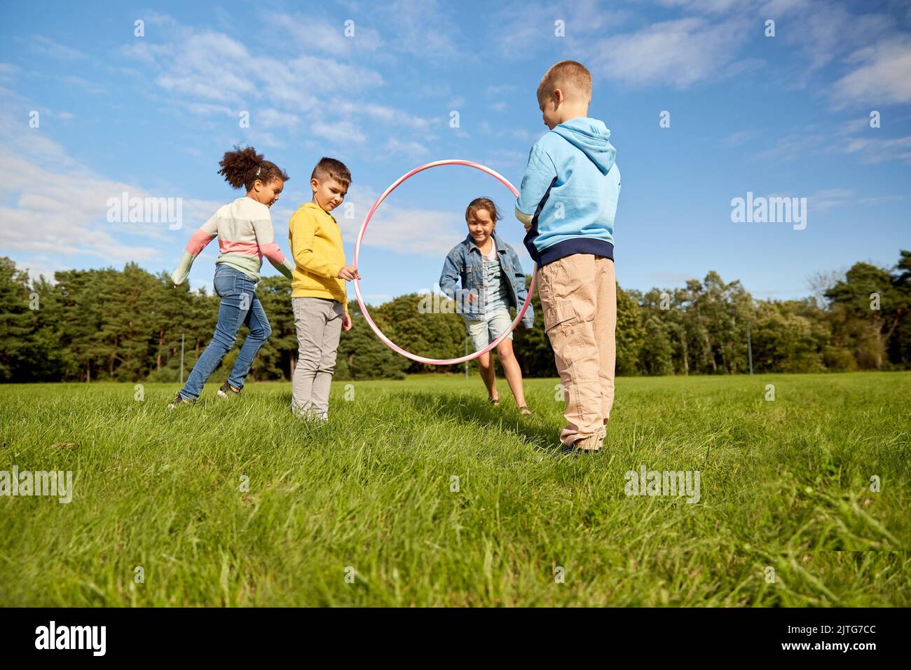 happy children playing game with hula hoop at park Stock Photo - Alamy