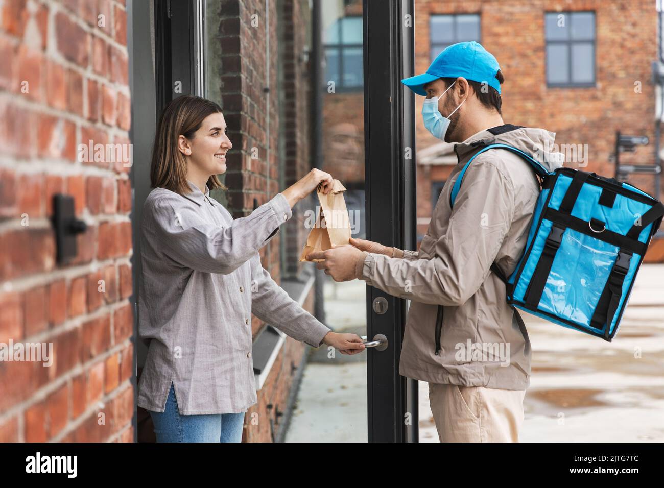 food delivery man in mask giving order to customer Stock Photo - Alamy