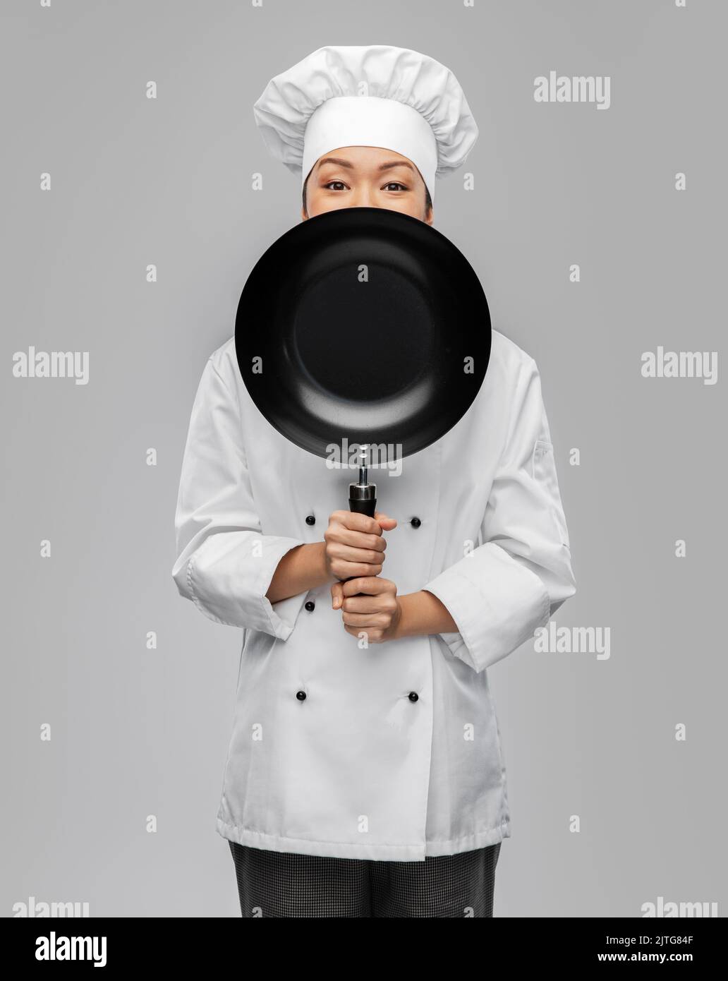 female chef peeking out from behind frying pan Stock Photo - Alamy