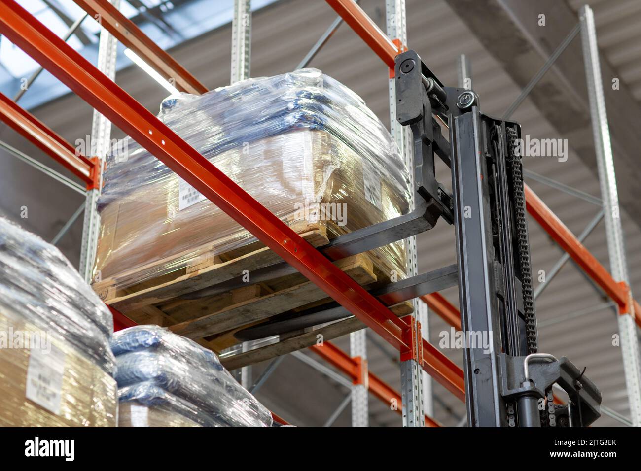 forklift loader loading cargo to warehouse shelves Stock Photo - Alamy