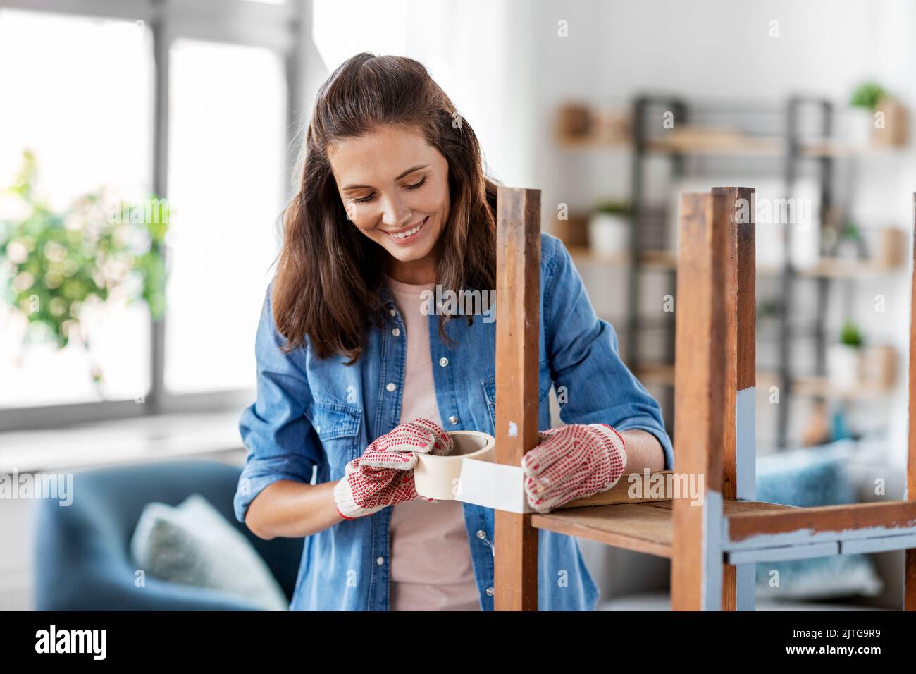 woman sticking masking tape to table for repaint Stock Photo - Alamy