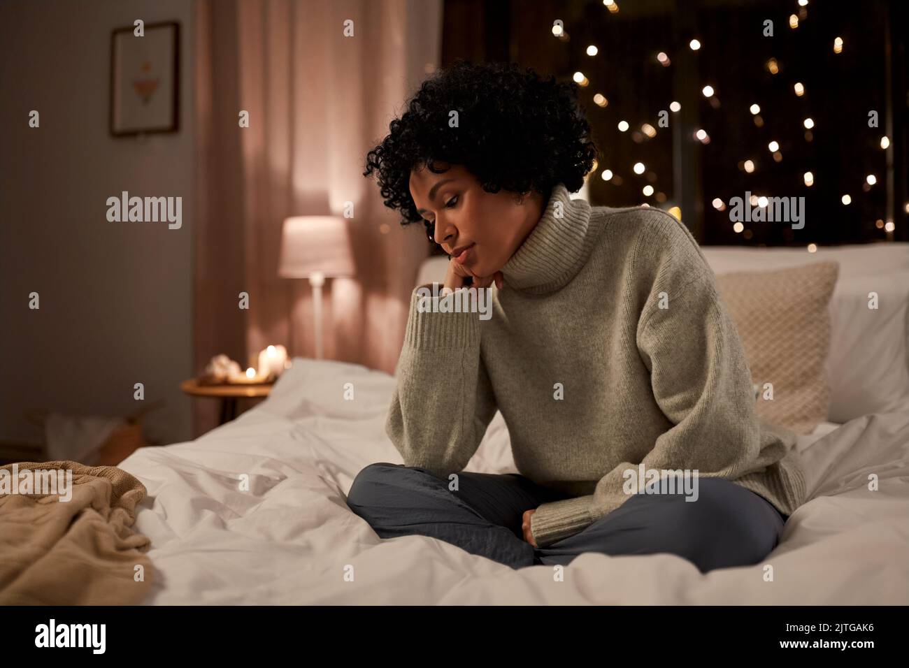 sad woman in sweater on bed at home at night Stock Photo - Alamy