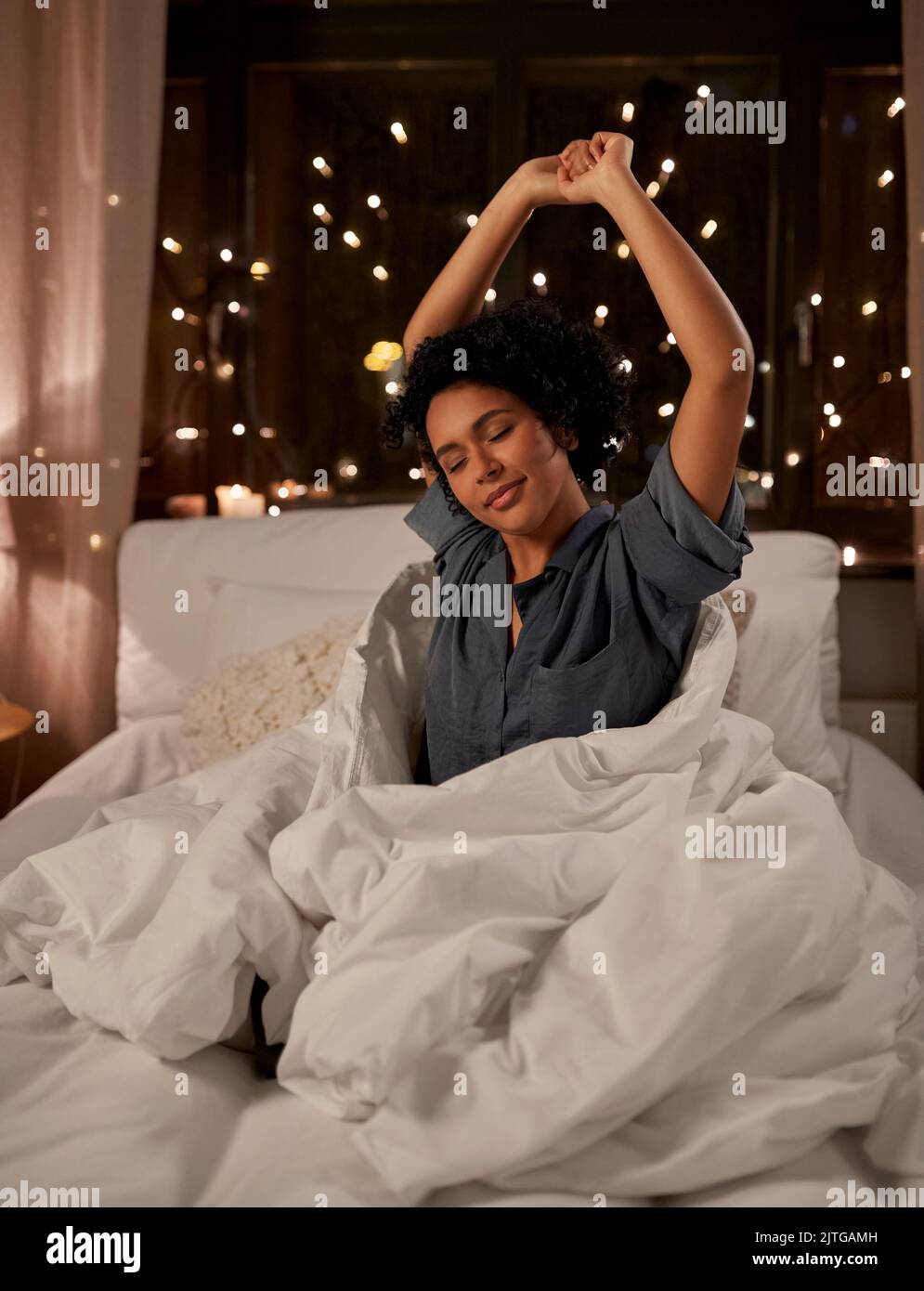 sleepy woman stretching in bed at night Stock Photo - Alamy