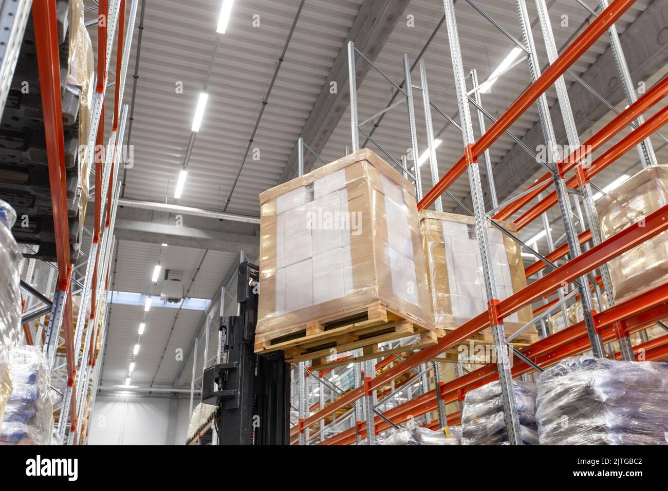 forklift loader loading cargo to warehouse shelves Stock Photo - Alamy