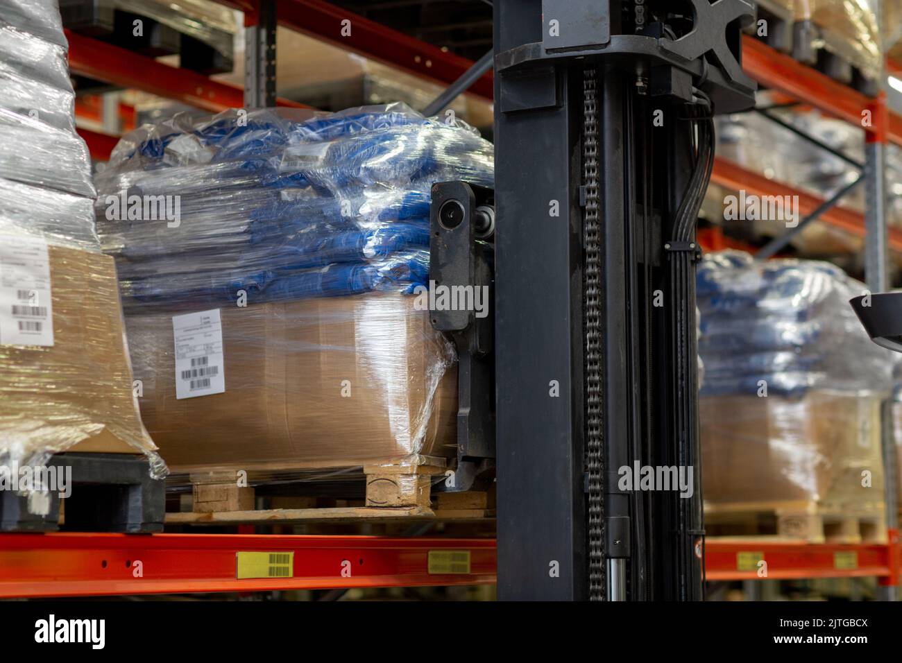 forklift loader loading cargo to warehouse shelves Stock Photo - Alamy
