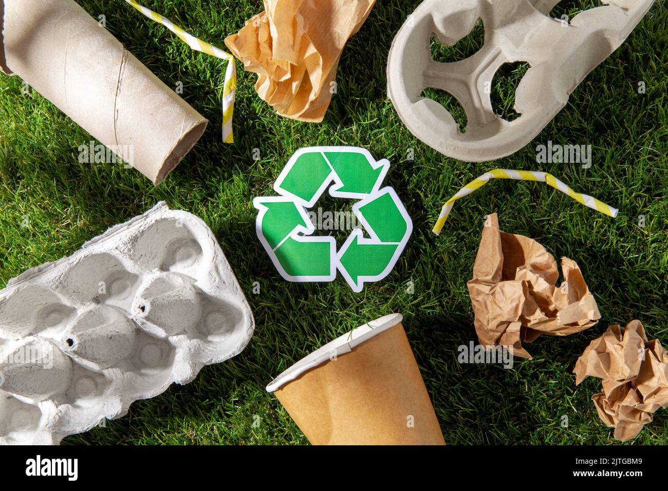 green recycling sign and paper waste on grass Stock Photo - Alamy