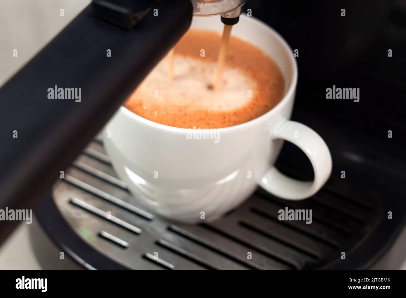 Glass cup standing on the grating of black coffee machine and coffee ...