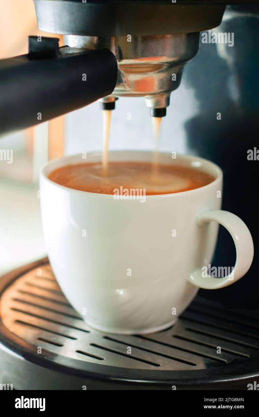 Glass cup standing on the grating of black coffee machine and coffee ...