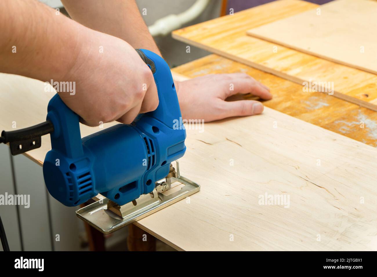 Image of a man hand using electric jigsaw. close up process of cutting ...