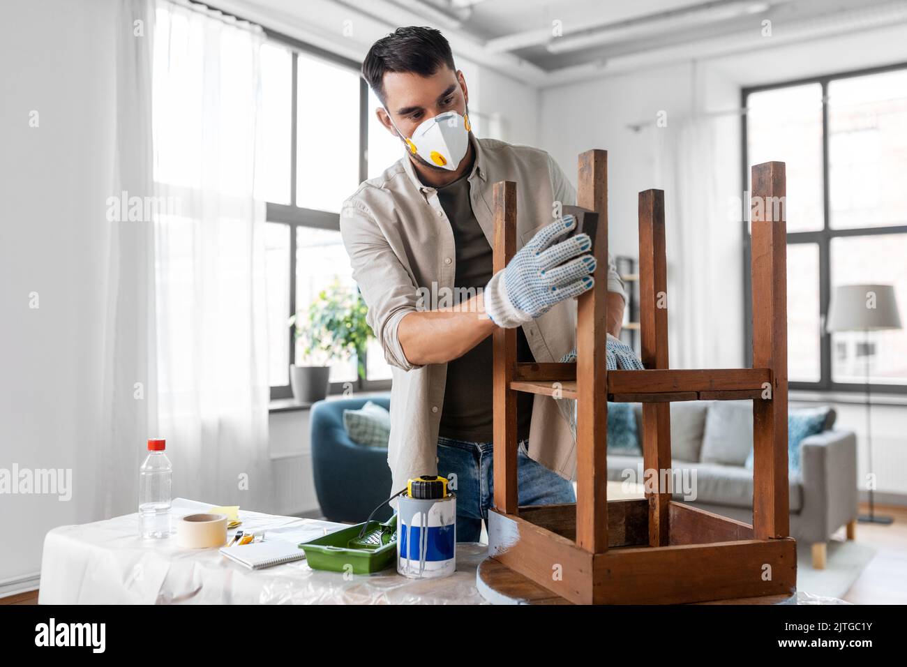 man in respirator sanding old table with sponge Stock Photo - Alamy