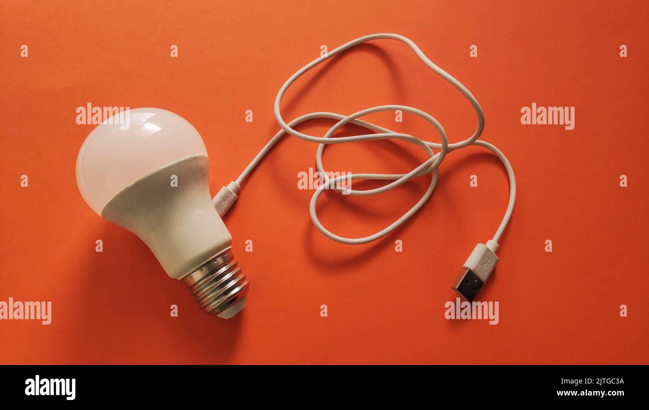 A phone charger and a light bulb on a colorful paper background Stock ...